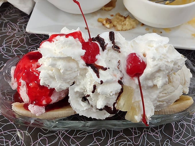 A banana split that doesn't whisper "dessert" but shouts it from the rooftops – ice cream mountains draped in whipped cream avalanches and cherry-topped glory.