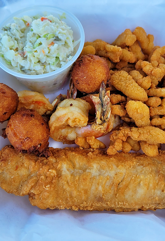 A seafood medley that sings in perfect harmony—crispy clam strips, succulent shrimp, and golden hush puppies performing alongside the coleslaw's refreshing encore.
