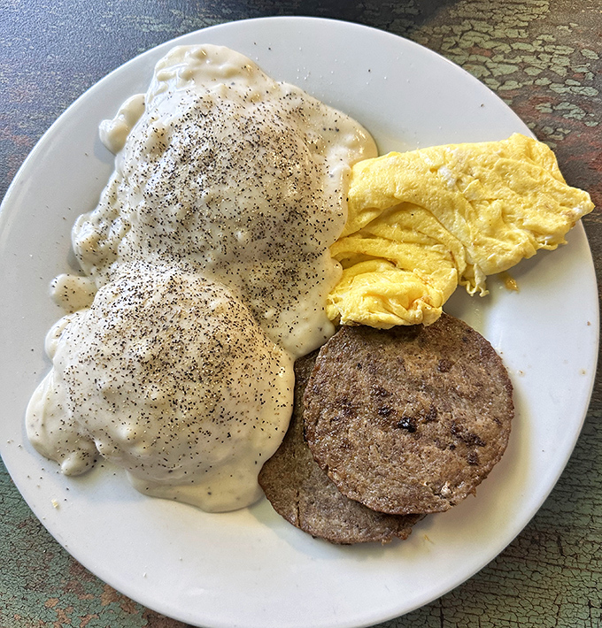 Biscuits smothered in gravy alongside perfectly scrambled eggs and sausage—the breakfast trinity that's converted more diet plans than Sunday sermons.