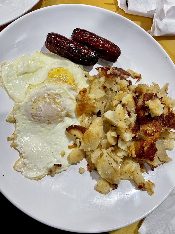 The classic American breakfast trinity: eggs sunny-side up, crispy hash browns, and sausage links that have achieved that perfect snap when you bite into them.