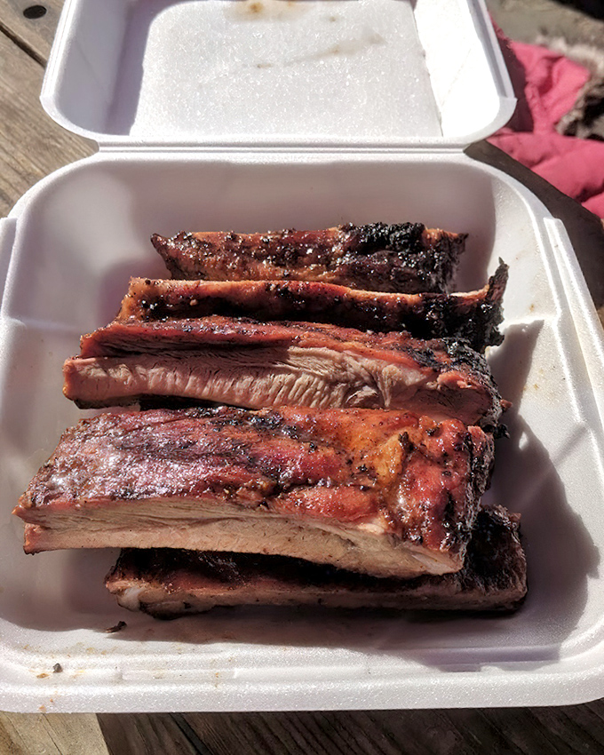 These ribs have the kind of bark that makes tree bark jealous—a crackling exterior giving way to meat that's spent hours getting acquainted with smoke.