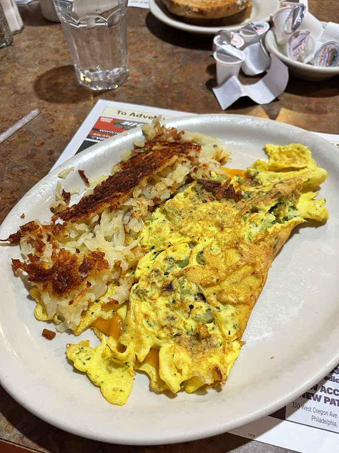 An omelet that doesn't just contain vegetables—it celebrates them in a fluffy yellow embrace of cheesy perfection.