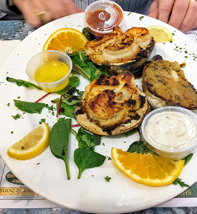 Broiled crab cakes presented with the ceremony they deserve—golden-brown treasures surrounded by citrus slices like culinary spotlights.