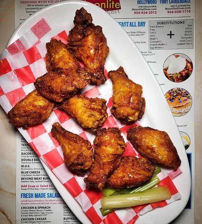 Fried chicken wings with a crunch so satisfying you'll hear it echo in your dreams—served on checkered paper because some traditions matter.