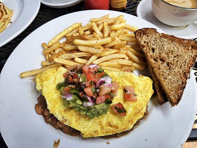 When an omelet meets California sunshine – fresh ingredients piled high with a side of perfectly crisped toast and golden fries.