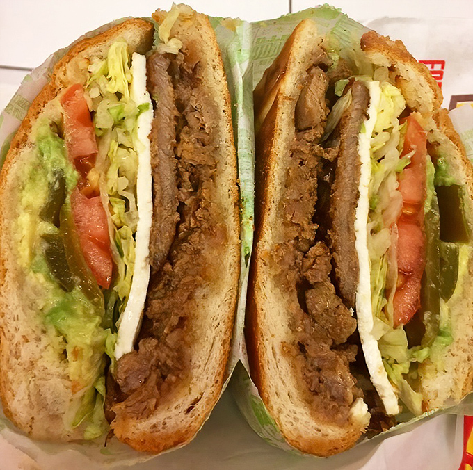 When a sandwich becomes art: layers of seasoned meat, fresh vegetables, and creamy avocado create a masterpiece that belongs in both the Louvre and your stomach.