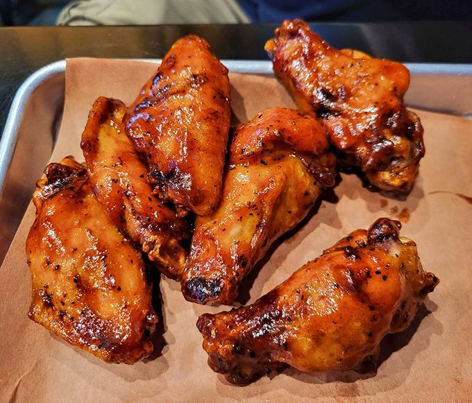These wings aren't just cooked—they're transformed through smoke and fire into crispy-skinned vessels of juicy perfection.