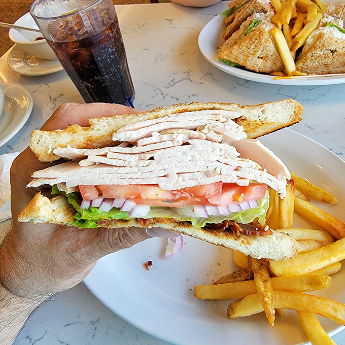 Behold the architectural marvel that is a proper club sandwich—where turkey, bacon, and vegetables achieve perfect structural harmony.