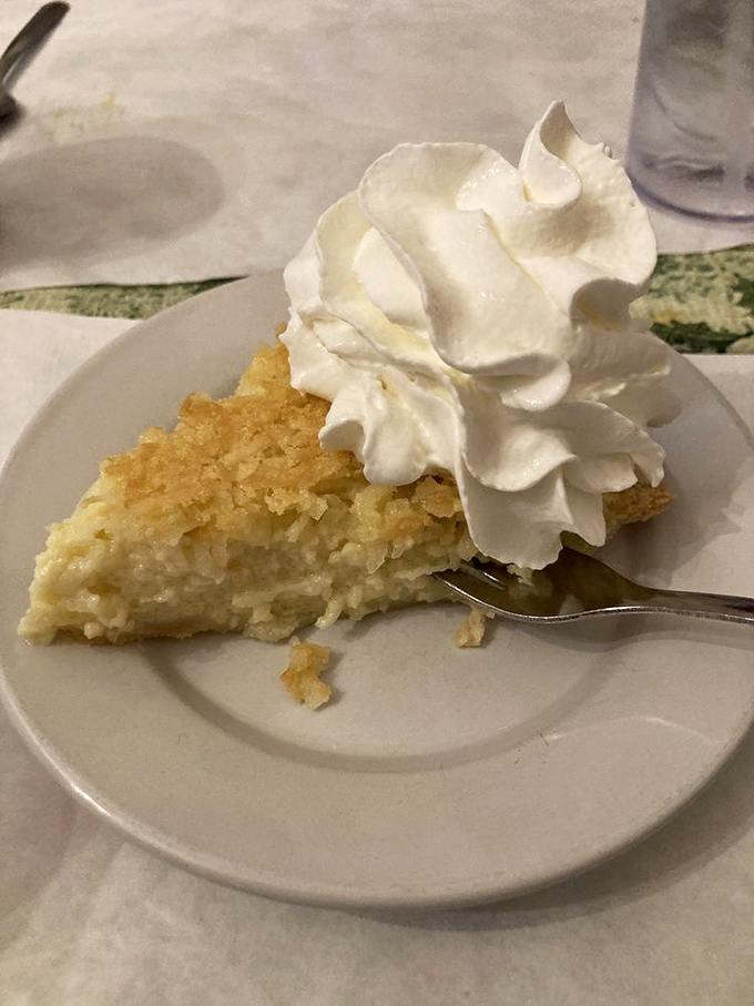 Coconut pie topped with a cloud of whipped cream—proof that sometimes the simplest desserts create the most profound happiness.