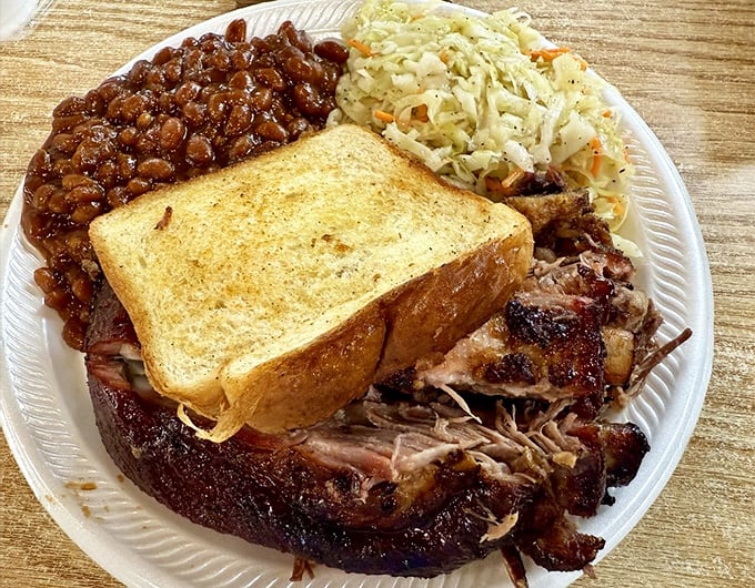 The barbecue plate that dreams are made of—pulled pork with perfect bark, baked beans swimming in sweet-savory sauce, and coleslaw for that essential crunch factor.