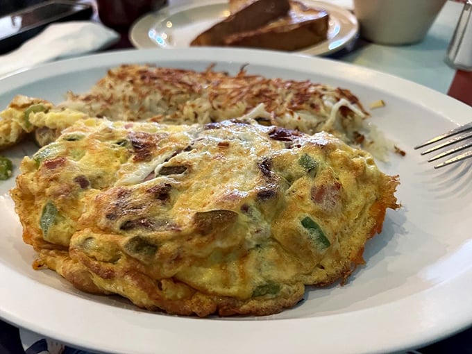 This omelet didn't just incorporate vegetables—it conquered them, creating a fluffy yellow fortress of breakfast perfection that demands your full attention.