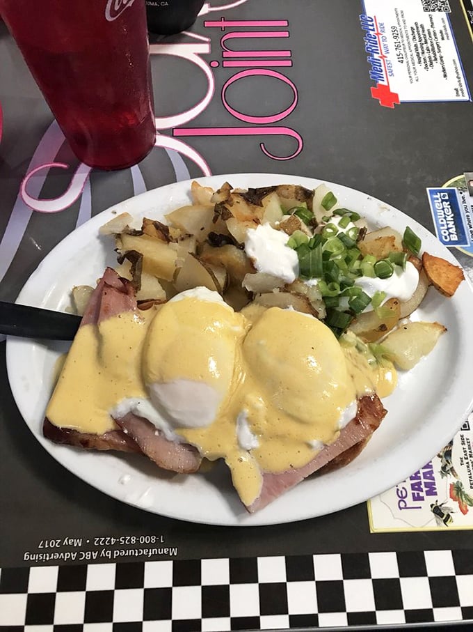 Eggs Benedict done right—perfectly poached eggs nestled on ham, draped in hollandaise, with home fries that didn't come from a freezer bag.