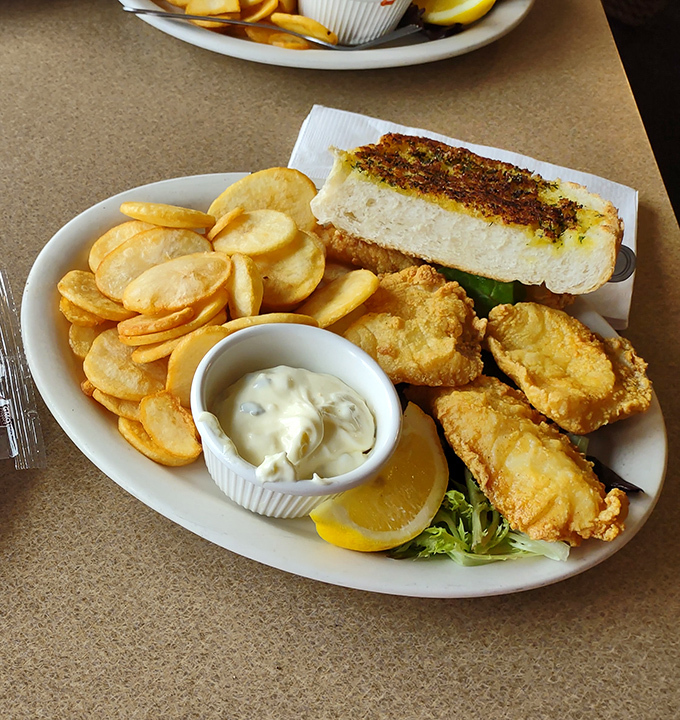 Fish and chips with a side of garlic bread—the holy trinity of coastal comfort food, executed with the precision of a culinary love letter.