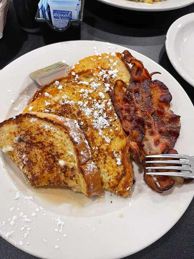 French toast dusted with powdered sugar and paired with bacon that's achieved that mythical balance between crispy and chewy—breakfast nirvana exists!