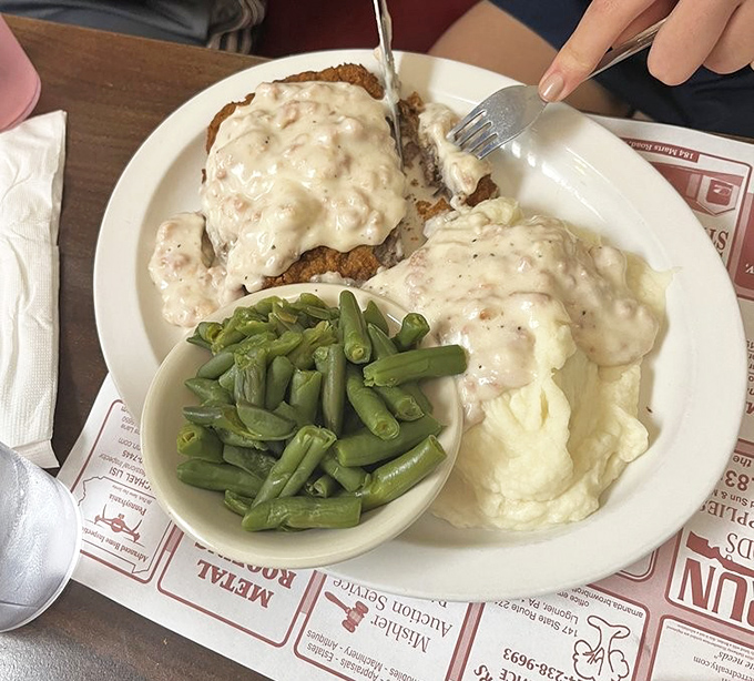 Country fried steak smothered in peppery gravy with green beans on the side—a plate that whispers "nap time" before you've even finished.