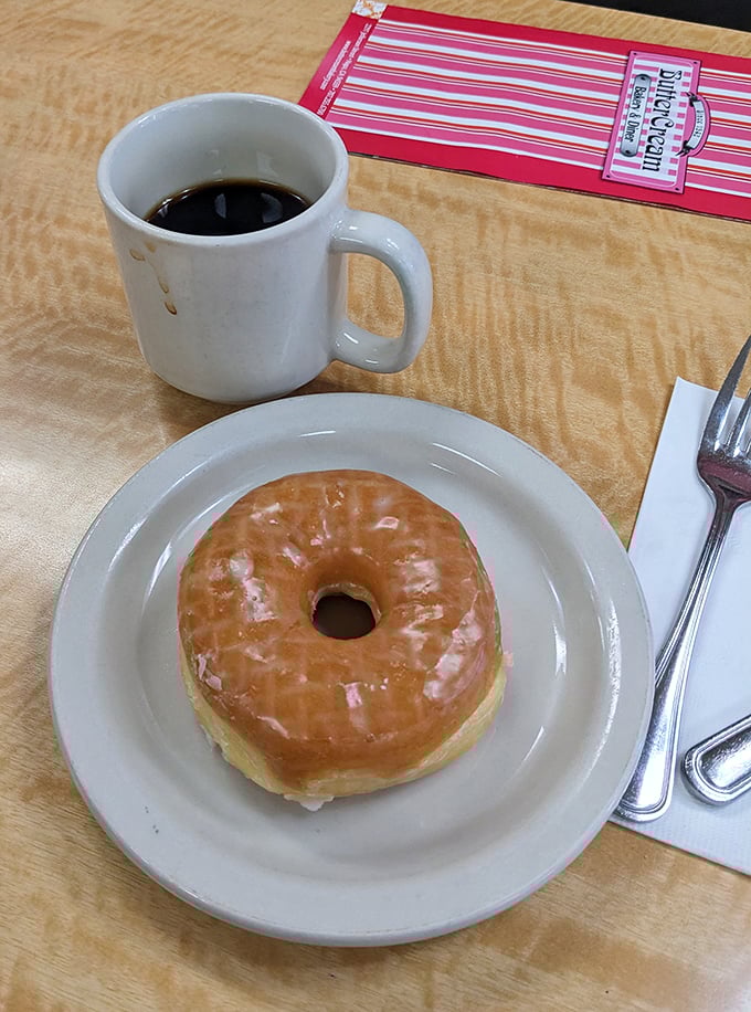 The glazed donut and coffee combo—civilization's most perfect pairing since Fred and Ginger, displayed on a diner plate that's seen thousands of happy mornings.