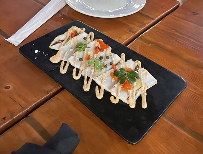 The calamari carpaccio arrives like modern art on a plate—proving that not all heroes of the sea wear capes or breading.