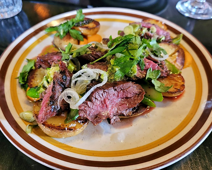 Hanger steak cooked with the respect it deserves—medium-rare perfection resting on grilled potatoes. Those fresh herbs aren't just pretty, they're necessary.