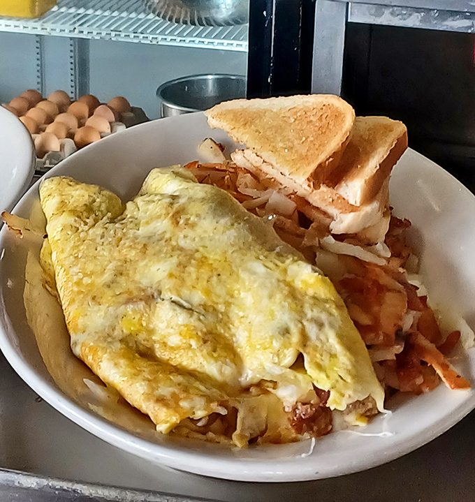 An omelet sprawled across a bed of hashbrowns like it owns the place—because at Hotcake House, it absolutely does.