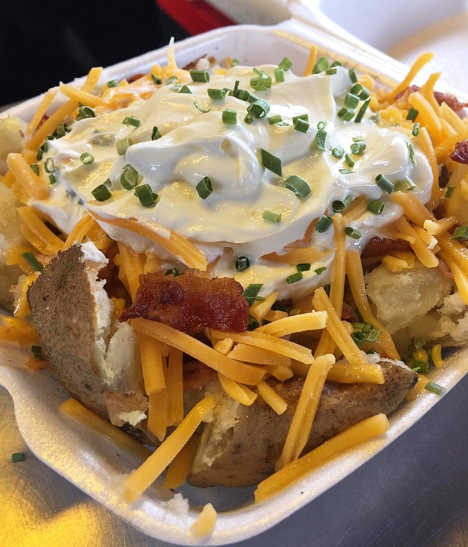 The loaded potato isn't just loaded—it's having an existential crisis under all those toppings. Cheese, scallions, and sour cream create a beautiful chaos.