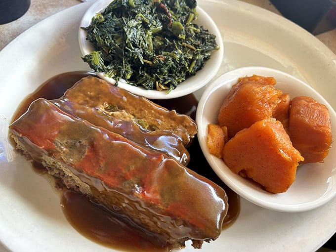 Meatloaf swimming in gravy with sides of greens and sweet potatoes—a plate that whispers "your grandmother would approve."