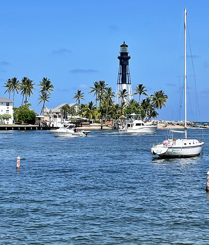 A postcard come to life – the lighthouse stands proudly among palm trees and boats, the quintessential Florida maritime scene.
