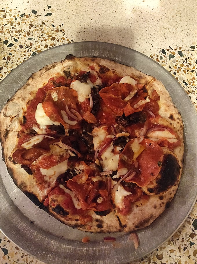 Pizza and pepperoni playing the perfect duet on a metal stage. The leopard-spotted crust tells you everything you need to know about proper wood-firing.