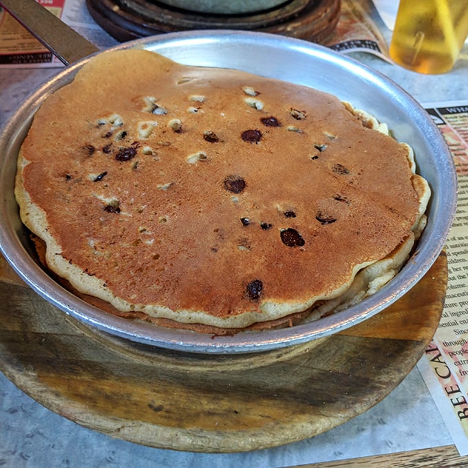 This isn't just any pancake—it's the heavyweight champion of breakfast, taking up the entire pan with blueberry freckles that wink at you with each bite.