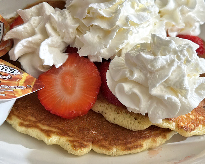 Pancake perfection isn't just about the fluff factor – it's the canvas of golden brown topped with fresh strawberries and clouds of real whipped cream.