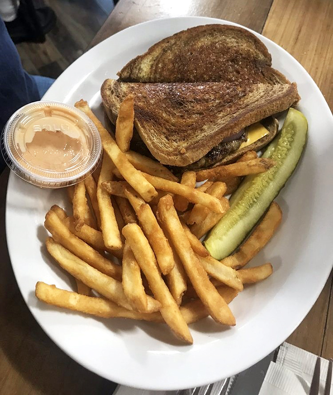 The patty melt – that glorious marriage of burger and grilled cheese – arrives with perfectly golden fries and a pickle spear standing guard.