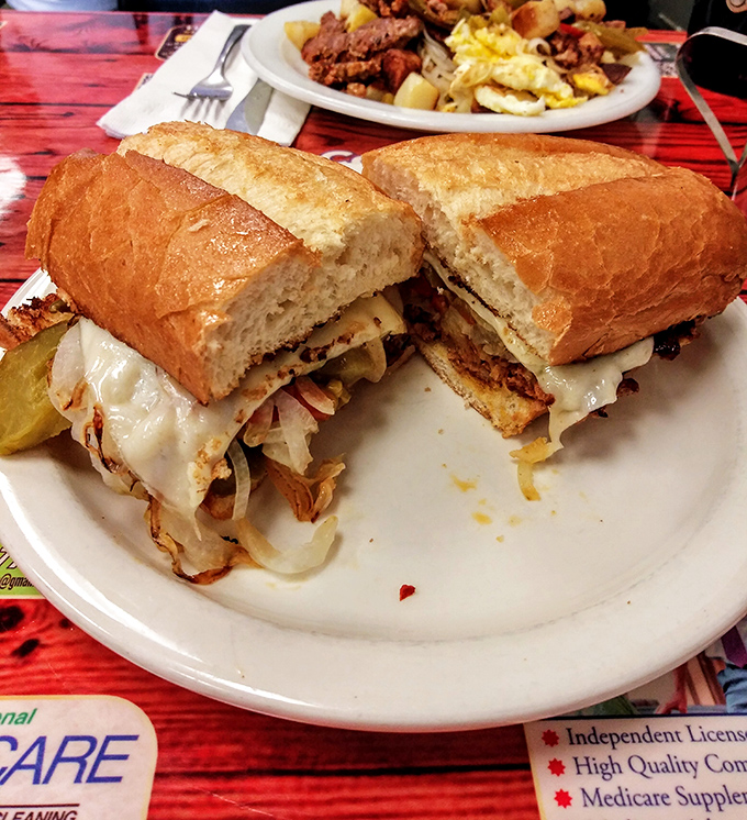 The sandwich that launched a thousand lunch breaks – a proper Pittsburgh cheesesteak on crusty bread that demands to be eaten, not photographed.