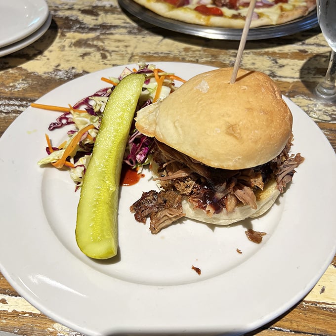 A pulled pork sandwich that doesn't need fancy tricks—just honest flavor, a pickle spear standing guard, and slaw for contrast.