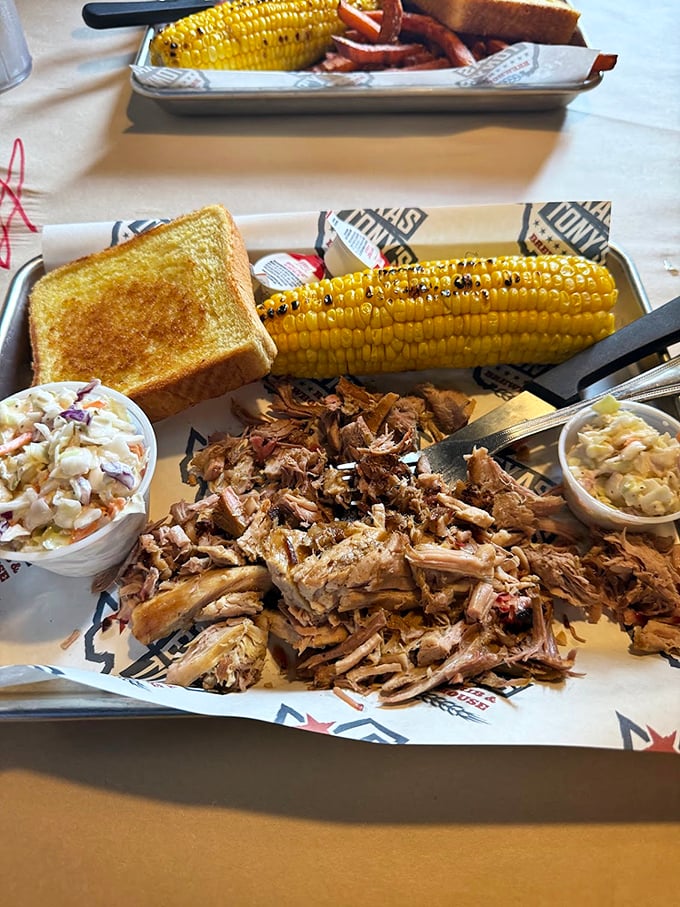 Pulled pork paradise on a plate—tender strands of smoky goodness alongside golden corn and creamy coleslaw. Napkins required, not optional.