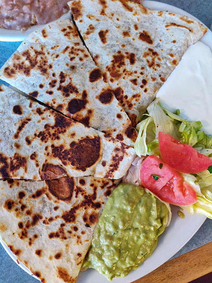 The humble quesadilla elevated to art form—perfectly crisped tortilla, melted cheese, and that dollop of guacamole waiting to take each bite to the next level.