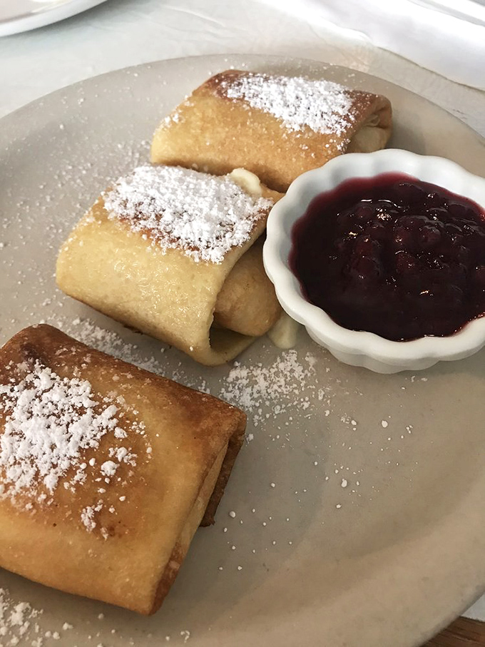 Russian Blintzes dusted with powdered sugar and served with berry compote—like delicate envelopes delivering sweet messages directly to your taste buds.