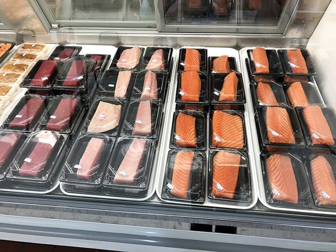 Fresh fish fillets lined up like colorful soldiers – ruby-red tuna, coral salmon, and pale white fish awaiting their moment of glory in your next meal.