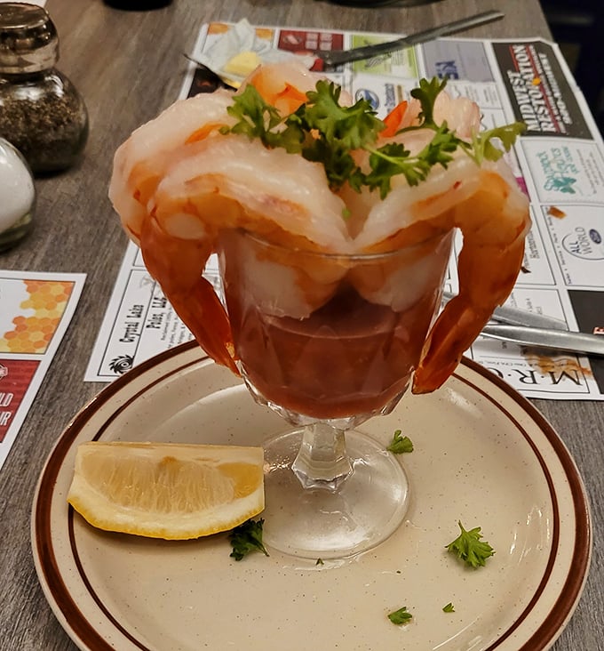 The shrimp cocktail arrives like royalty on a throne of ice, each jumbo shrimp perched proudly above a pool of zesty cocktail sauce.