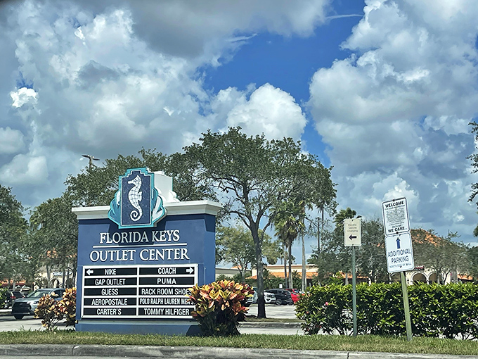 The marketplace's entrance sign stands like a retail lighthouse, guiding bargain hunters safely to shore from the highway seas.