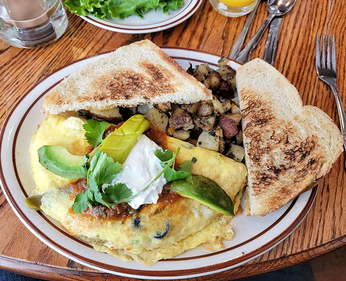 This isn't just an omelet—it's an edible postcard from flavor country, where avocado, sour cream, and perfectly folded eggs create breakfast harmony.