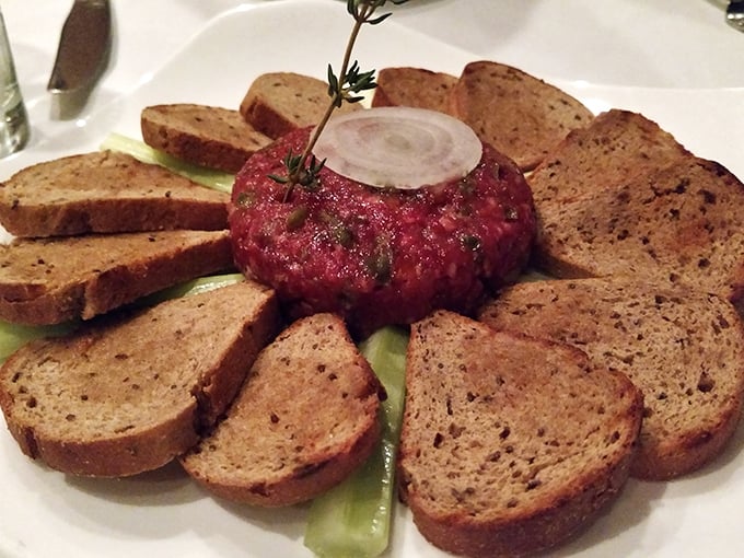 Steak tartare arranged like an edible sunflower. Raw beef never looked so civilized, surrounded by its bread petal entourage.