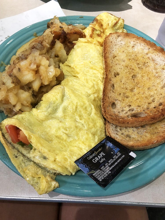 This isn't just an omelet—it's a fluffy yellow pillow of morning happiness alongside those famous lyonnaise potatoes that could steal the spotlight.