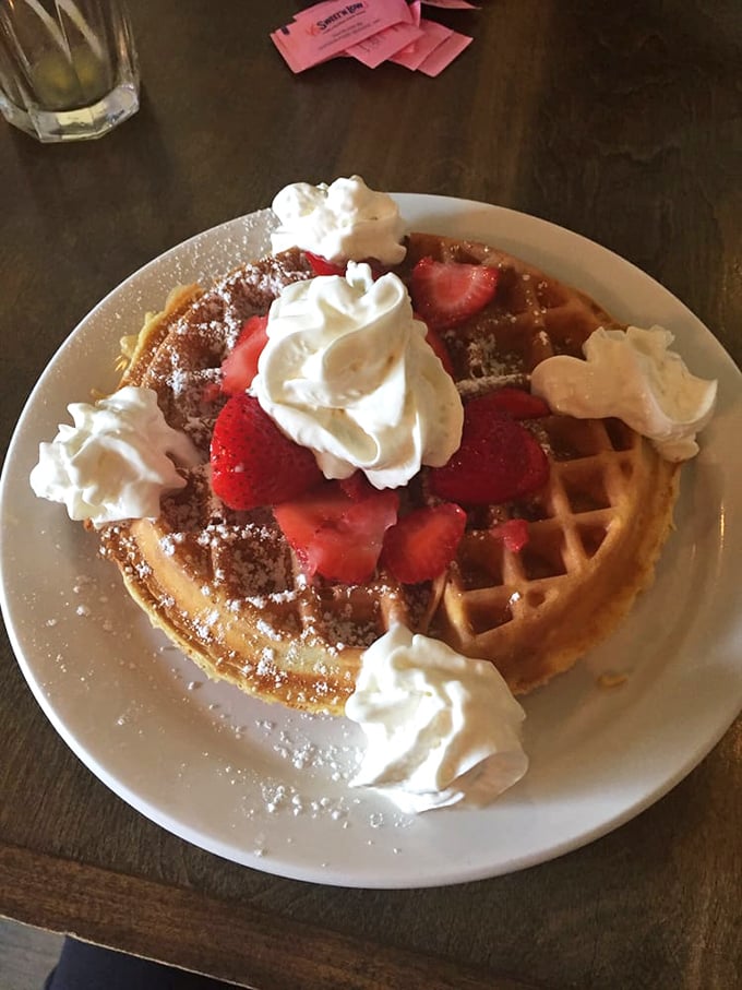 This Belgian waffle isn't just breakfast, it's architecture—a perfect grid of crispy exterior holding strawberries and whipped cream like edible jewelry.