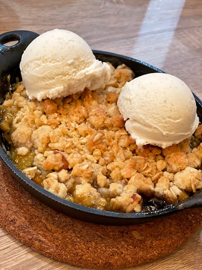 Apple crisp served in a cast-iron skillet with vanilla ice cream—proof that happiness is indeed a warm dessert.