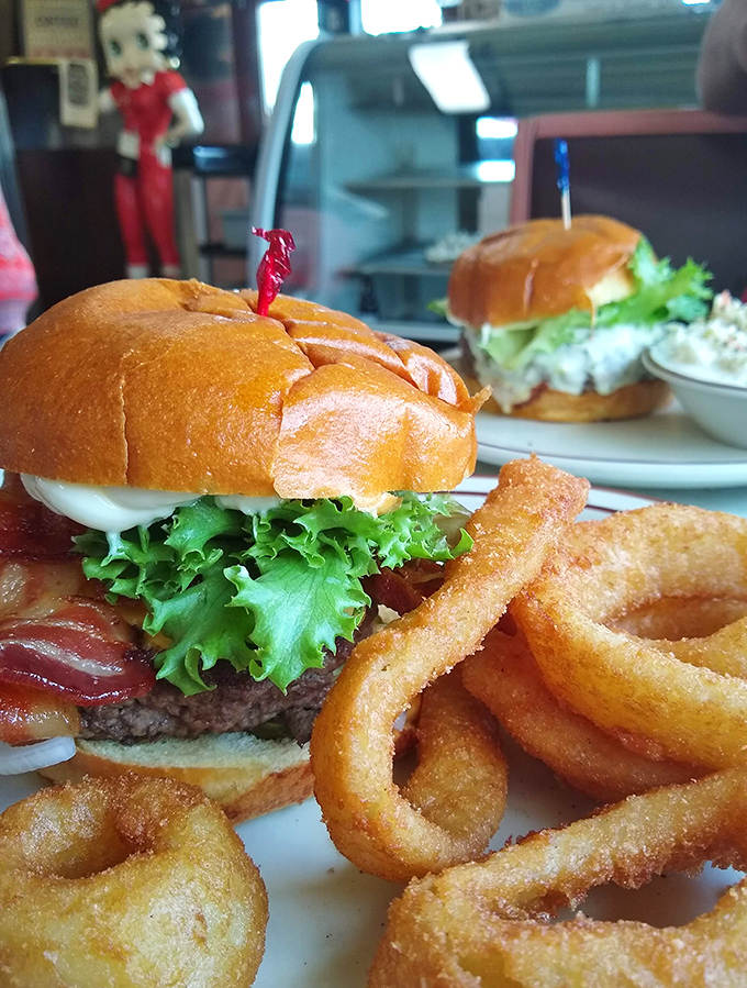 Burger artistry that puts fancy $20 downtown versions to shame. Those onion rings aren't just sides—they're halos of happiness.