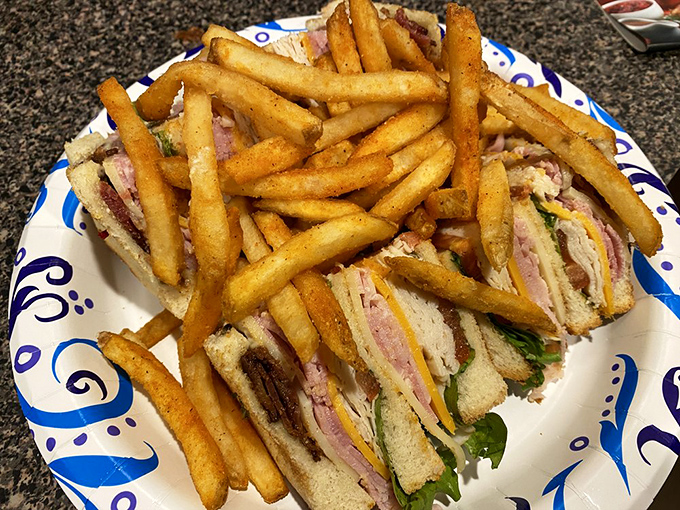 The club sandwich stands tall and proud, like the Eiffel Tower of lunch options. Those golden fries aren't sides—they're co-stars.