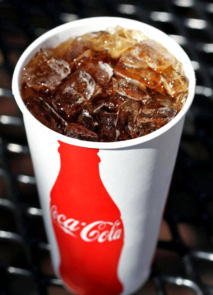 A classic Coca-Cola in a paper cup with ice—because sometimes the perfect accompaniment to sandwich perfection is refreshing simplicity.