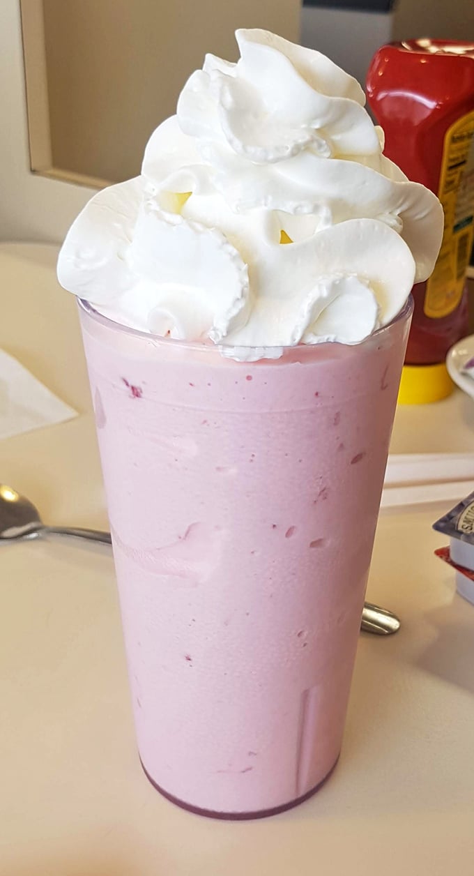 A strawberry milkshake towering with whipped cream—dessert masquerading as a beverage, and nobody's complaining about the deception.
