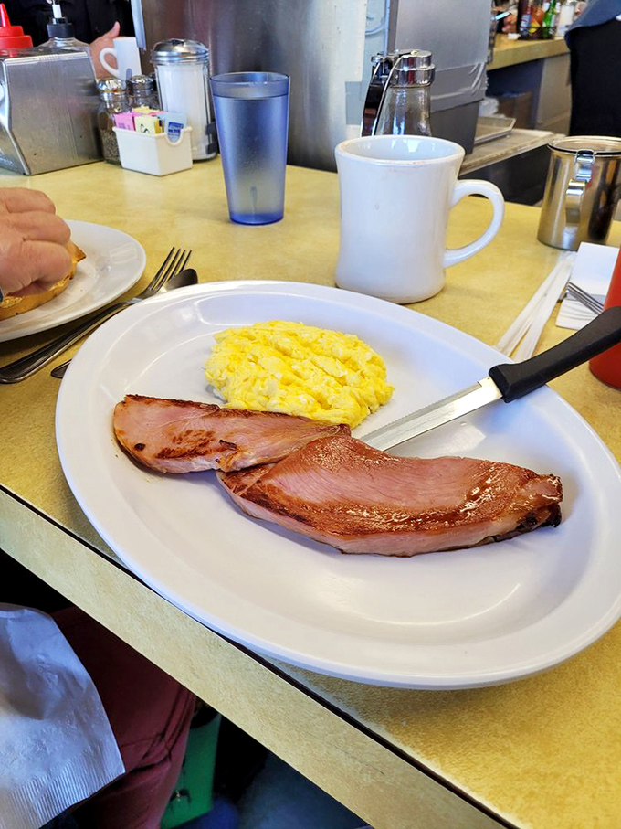 Sometimes simplicity is the ultimate sophistication. Perfectly scrambled eggs alongside ham that's been kissed by the grill—breakfast doesn't need to be complicated to be extraordinary.