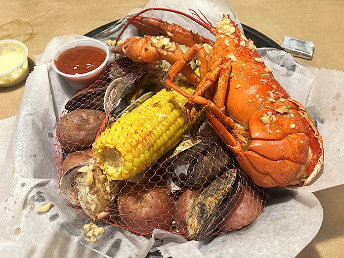 When a lobster arrives with corn and potatoes in tow, it's not just dinner—it's a coastal celebration wrapped in a convenient mesh bag.