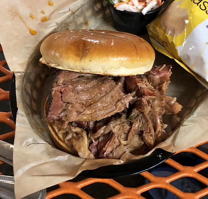This pulled pork sandwich isn't just a meal—it's an architectural marvel of tender meat that somehow manages to maintain its dignity despite being irresistibly sloppy.
